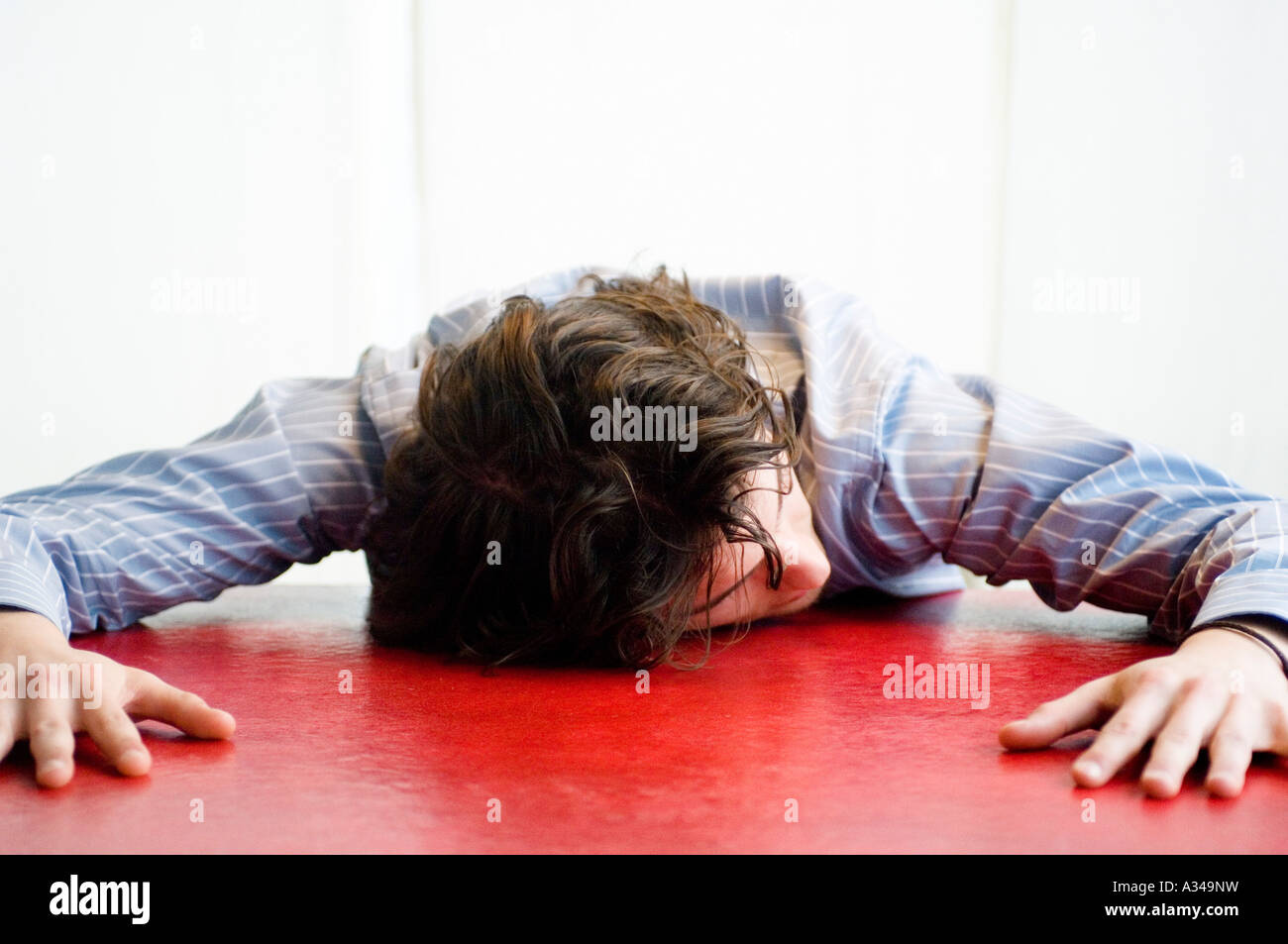 Young man sleeping leaning against a table Stock Photo - Alamy
