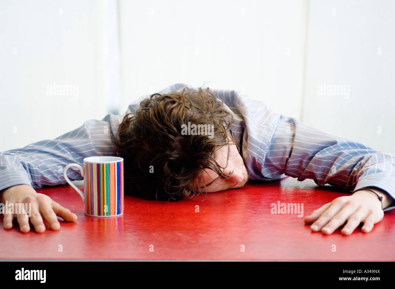 Young man sleeping leaning against a table Stock Photo - Alamy