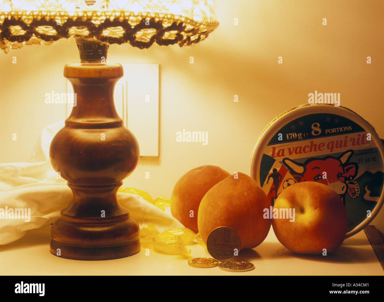 A still life composed of fruits and cheese is lit by a single lamp ...
