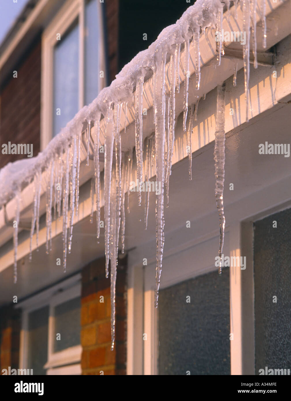 Icicles hanging from a house gutter evening sun Stock Photo - Alamy