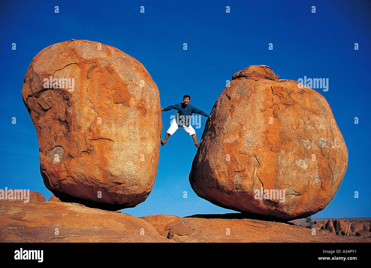 A man is standing between two rocks Stock Photo - Alamy