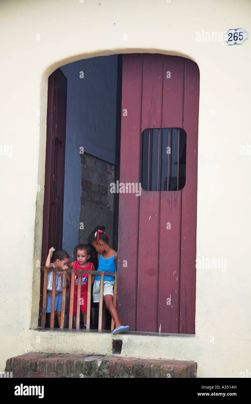 Three young children in large doorway, behind protective safety barrier ...
