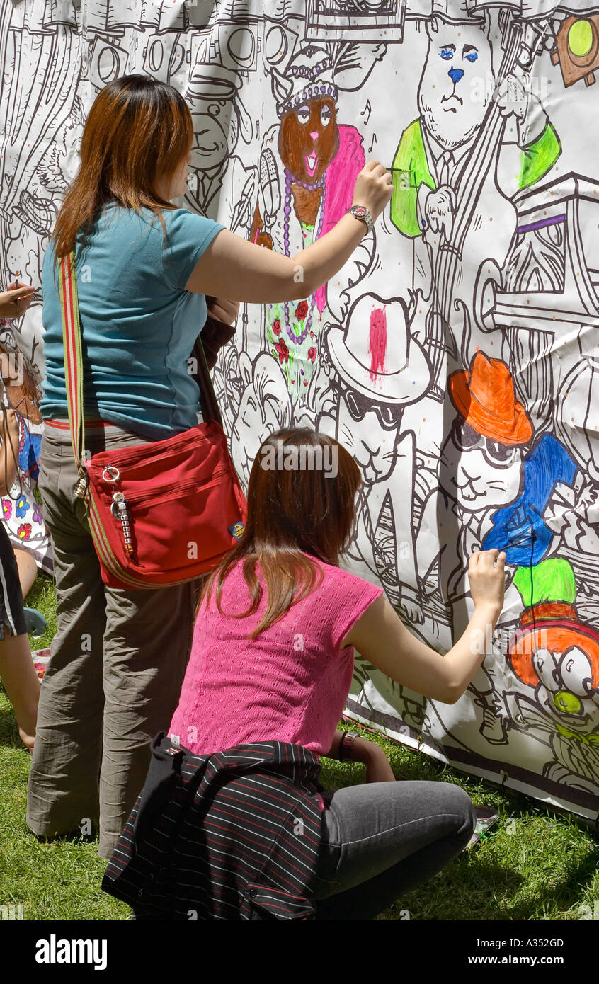 Caucasian kids paint in a coloring mural. Outdoor summer activity ...