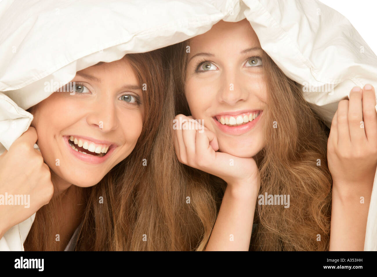 Laughing young women lying below duvet Stock Photo - Alamy