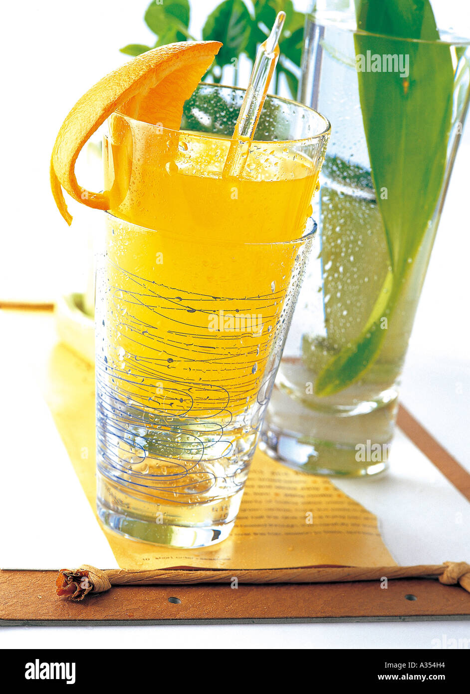 Yellow colored cocktail in a tall glass decorated with a slice of ...