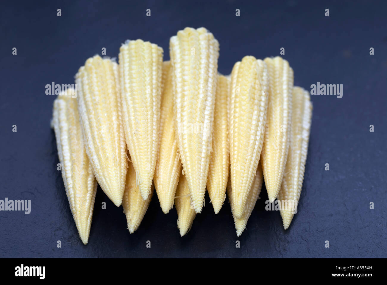 Baby sweetcorn on a dark background a "slate base Stock Photo - Alamy