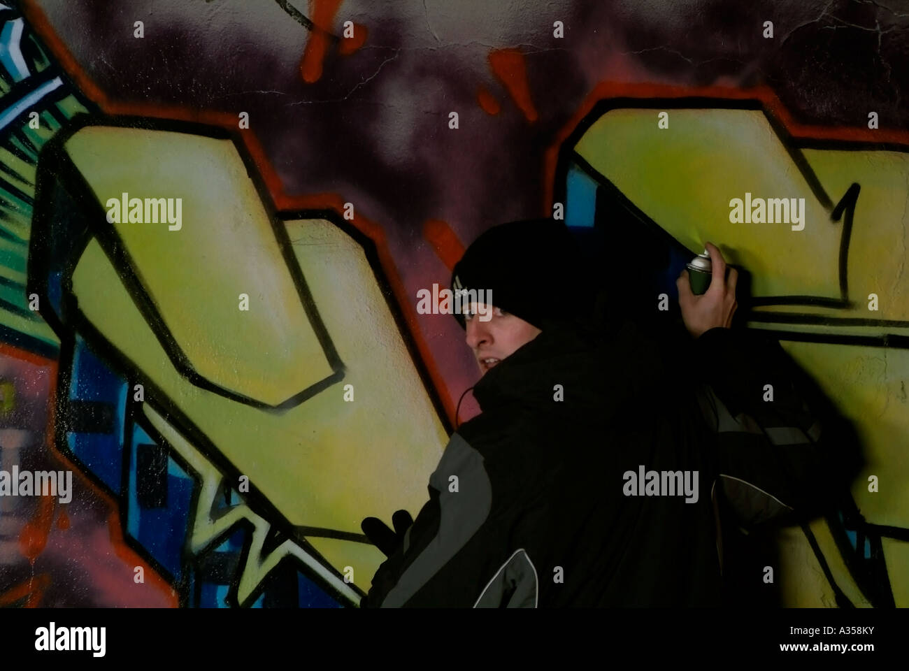 A graffiti artist getting caught painting on an alley wall at night ...