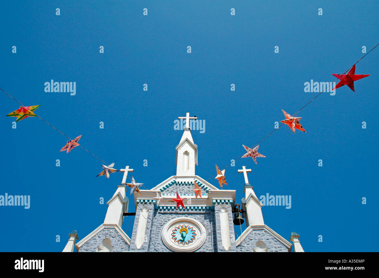 Looking up at strings of christmas stars and church spire against a ...