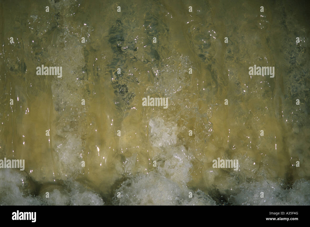 Silt ladened flood water over lowland river waterfall, Lincolnshire ...