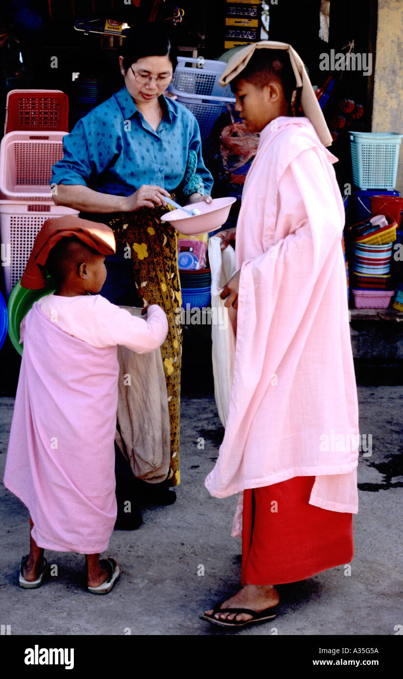 Burmese baby nun and older companion accept morning alms of daily food ...
