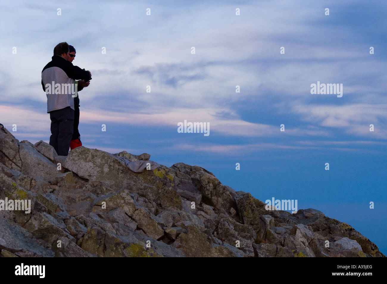Two hikers at dusk admiring the view from the summit, Krivan, Slovakia ...
