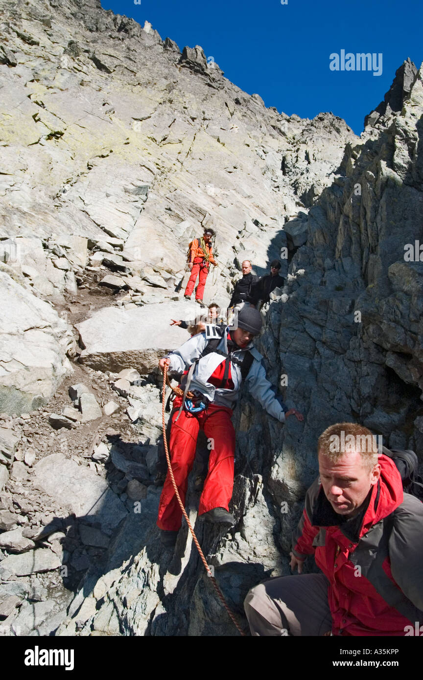 Group of tourists secured on a rope, descending from the Gerlach peak ...