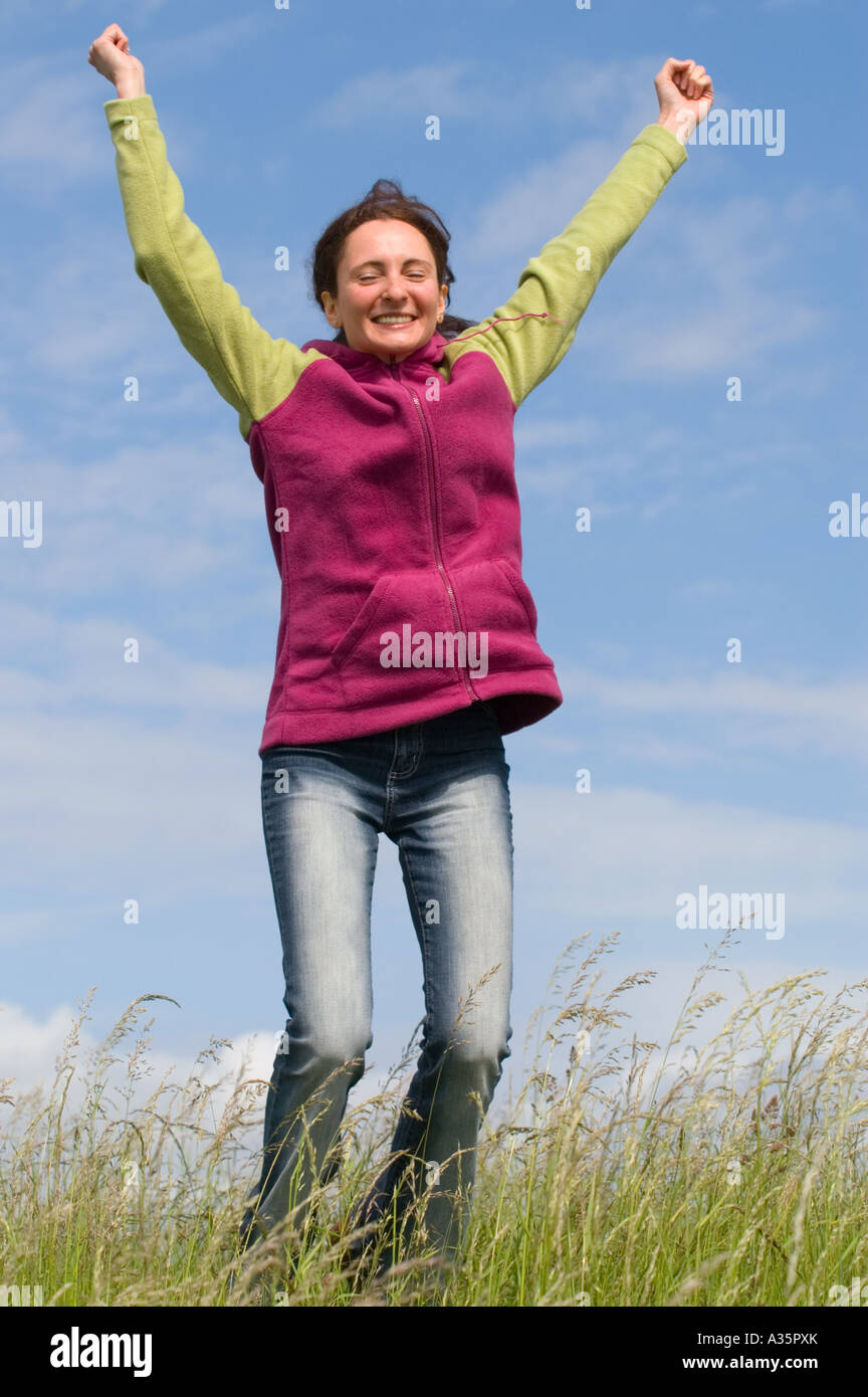 young woman cheering hooray in a meadow with blue sky above Stock Photo ...