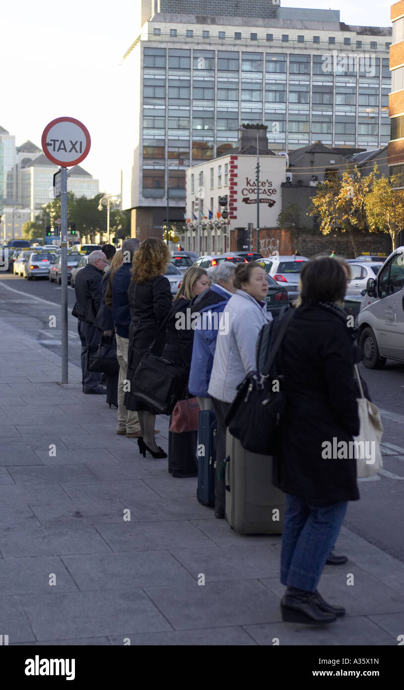 orderly line queue of people in a taxi rank standing on the footpath ...