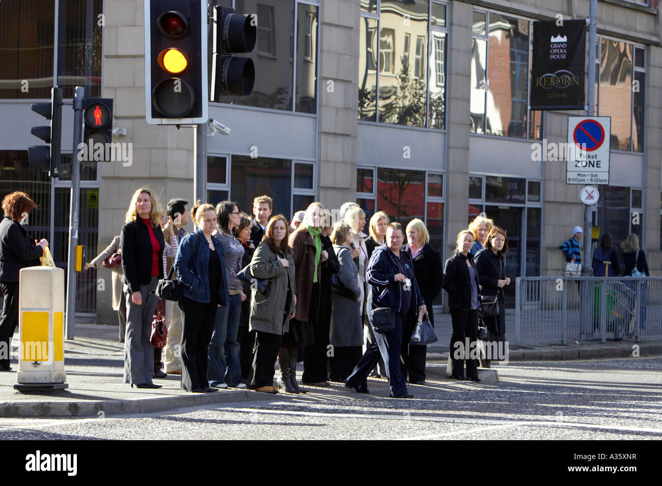 crowd of people waiting on light change to cross the road at traffic ...