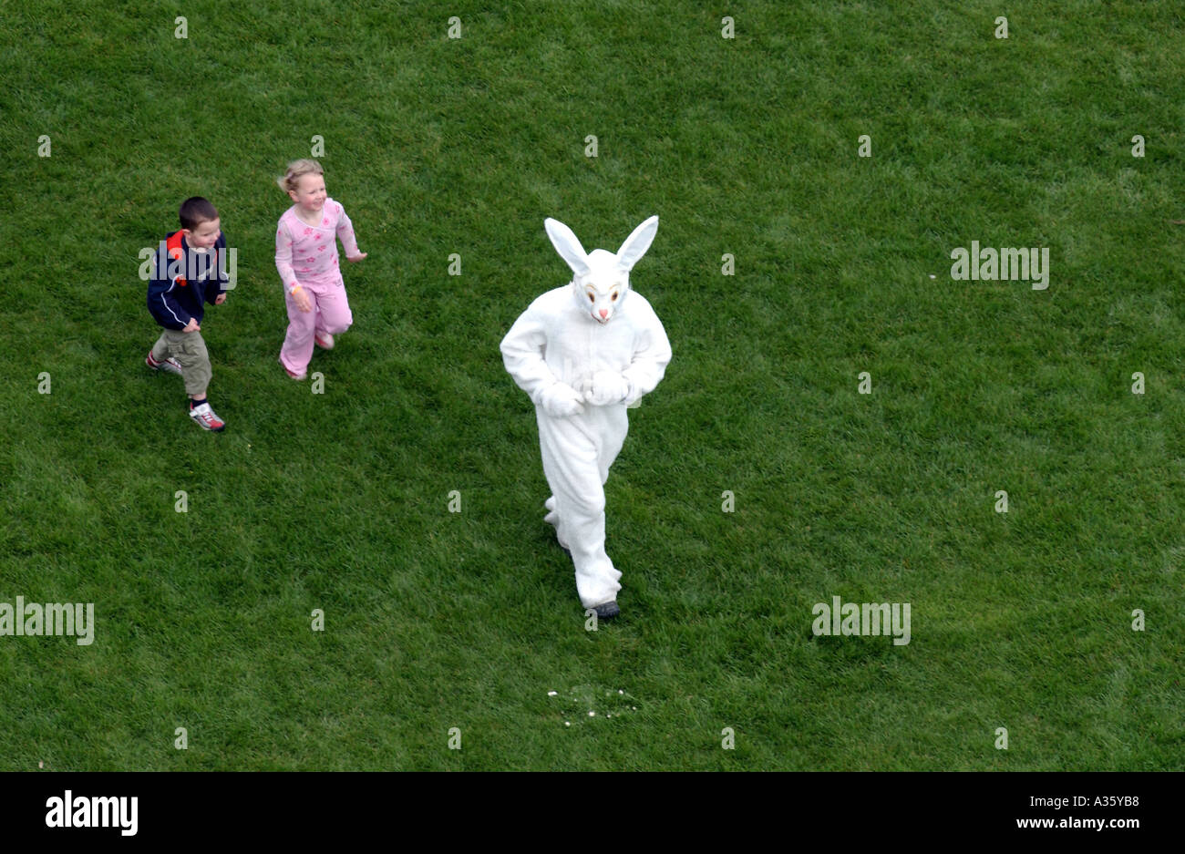 Two children chasing a giant Easter bunny Stock Photo - Alamy