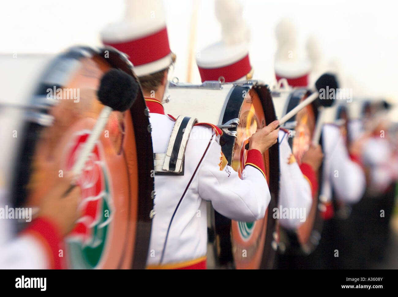 A line of percussion musicians are seen in colorful uniforms, marching ...