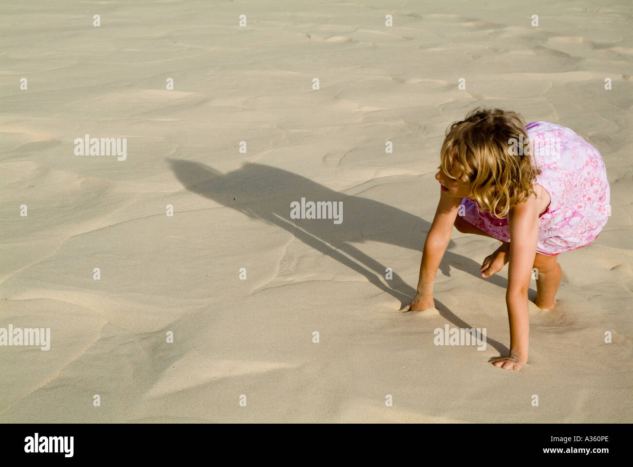 Girl bending down in the sand Pyla great sand dune in France Stock ...