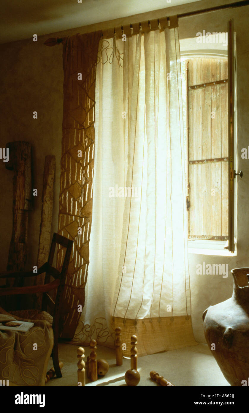 Linen drapes and white voile edged with hessian at window in country ...
