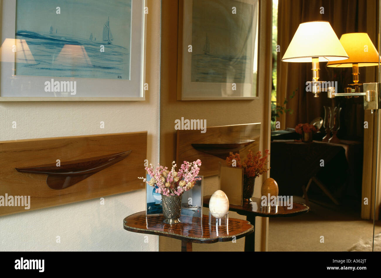 Close-up of small table corner of room with pictures and mirrored wall ...