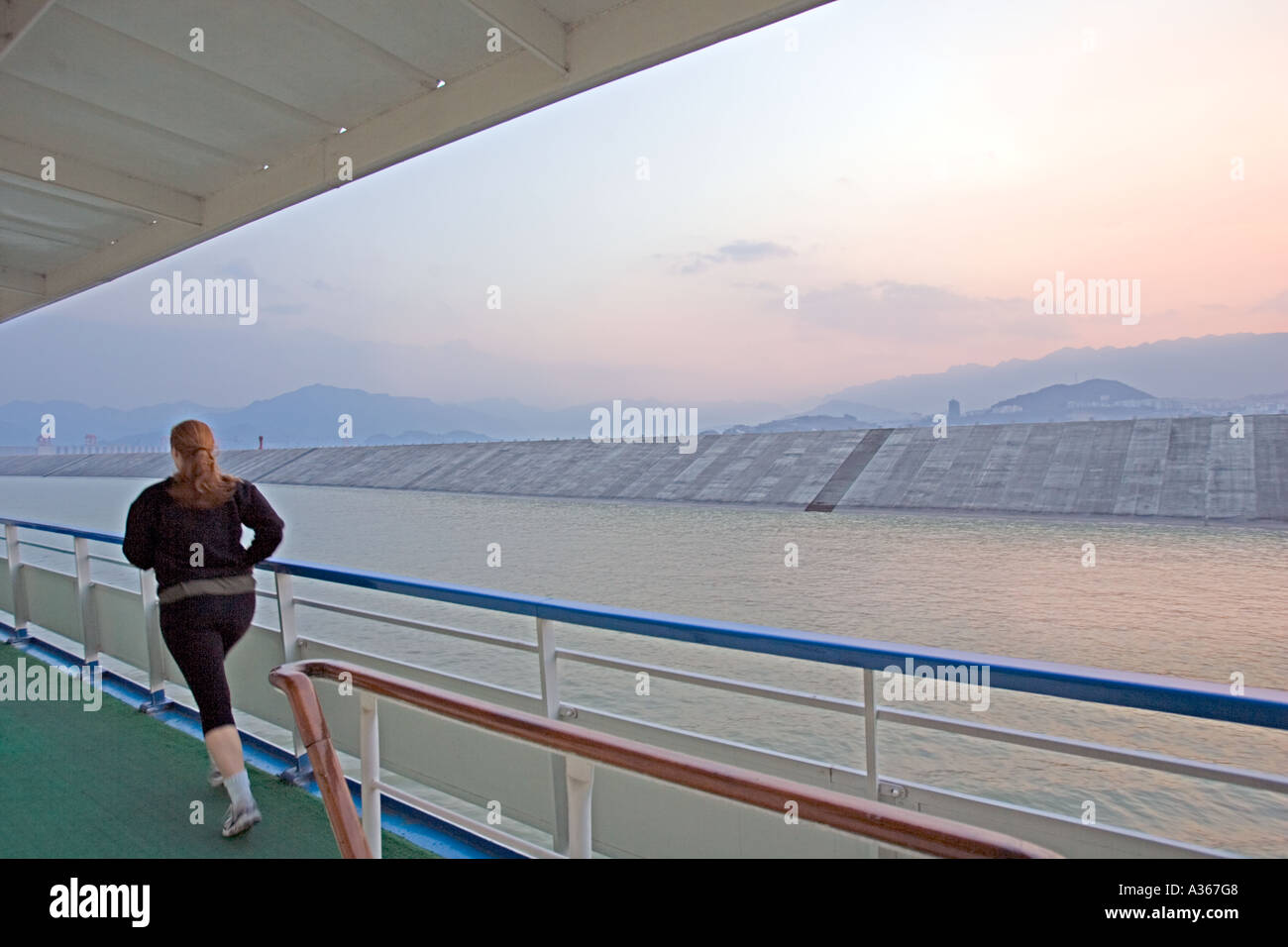 CHINA YANGTZE RIVER SANDOUPING Tourist jogs on deck at sunset as ...