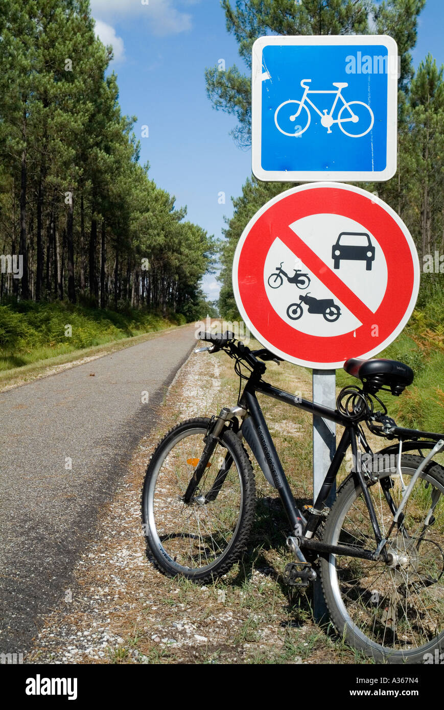 Bicycle parked against a road signs on a bicycle track passing through ...