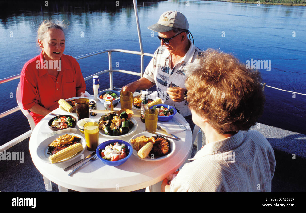 Three people enjoy dinner aboard a house boat on the Suwannee River in ...
