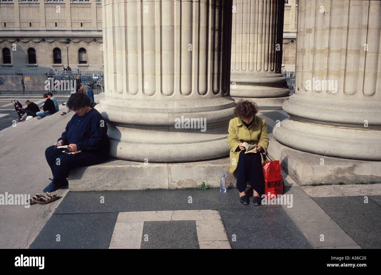 People sitting against a column Stock Photo - Alamy