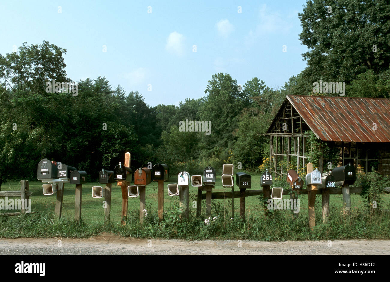 A row of a bunch of mailboxes stand by a rural road in front of an old ...