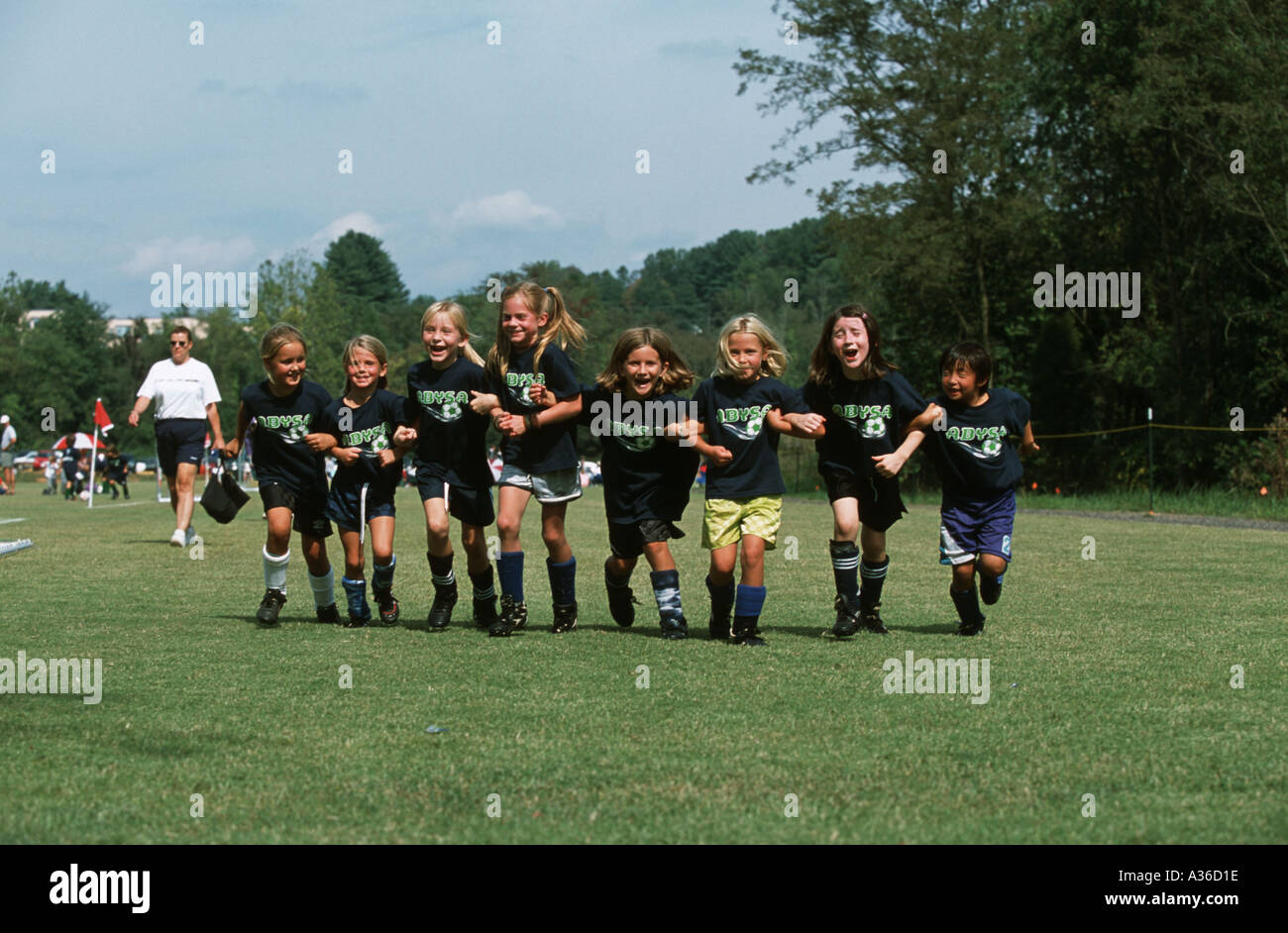 A team of girls wearing blue soccer uniforms run gather around their ...