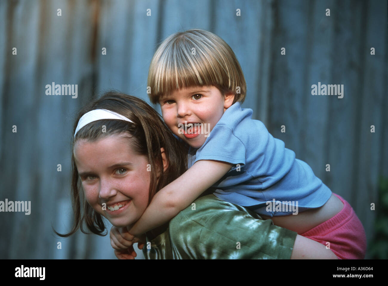 A ten year old girl holds her toddler sister on her back piggy back ...