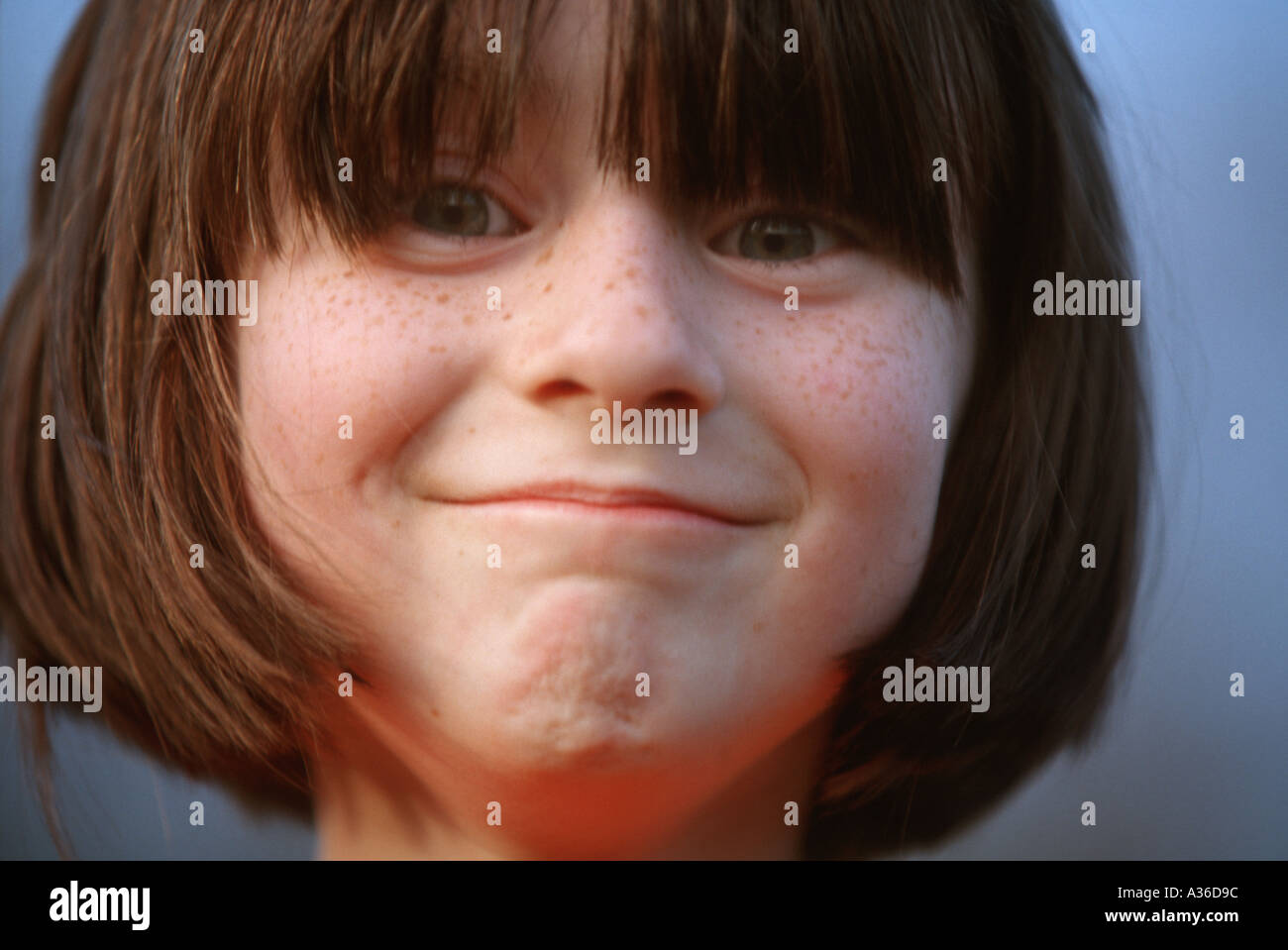 A young girl with short brown hair has an impish grin in this close up ...