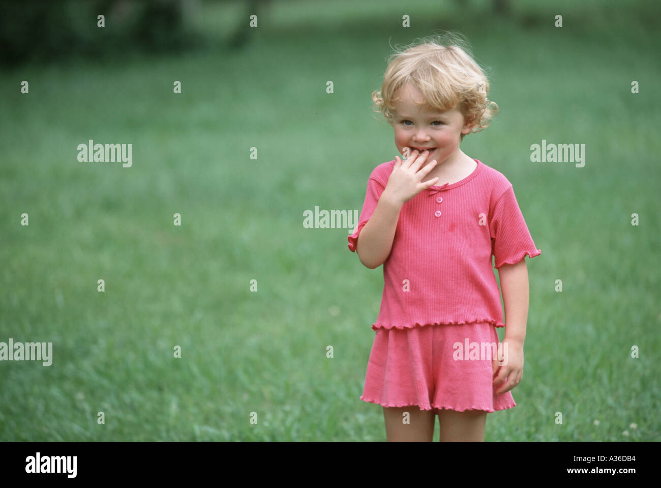 a cute young girl wearing a bright pink outfit smiles coyly at the ...