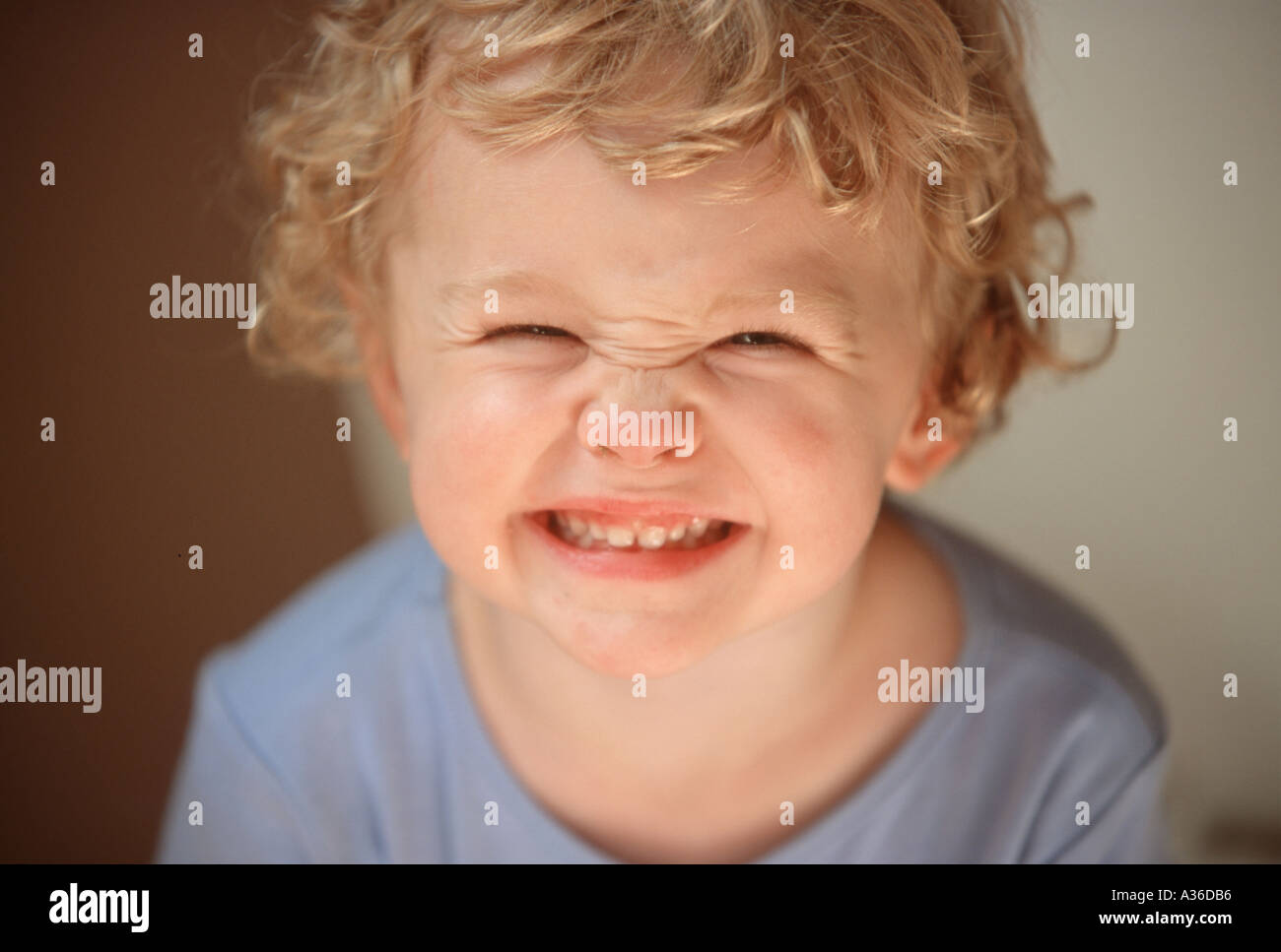 A cute young girl with blonde curls is grinning proudly at the viewer ...