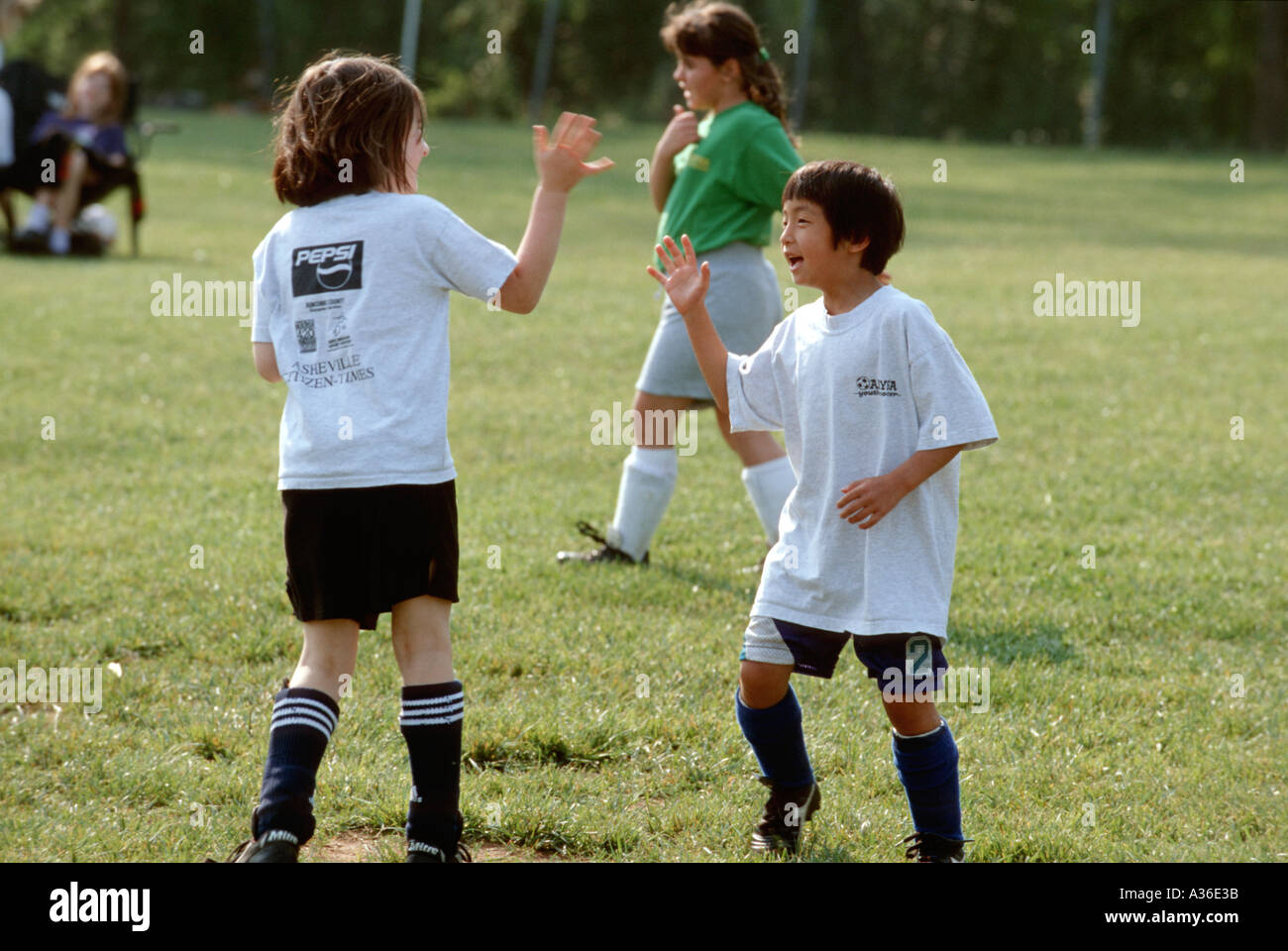 Two girls that are teamates on a soccer team slap hands in victory with ...