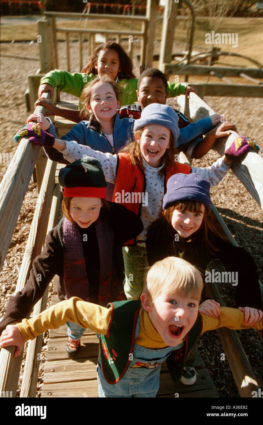 A group of children are lined up on a swinging bridge in a playground ...