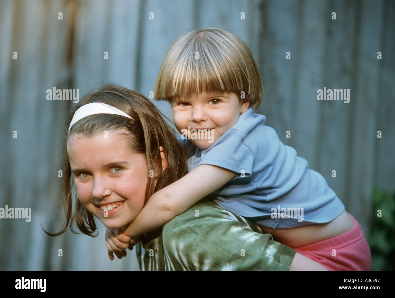 A young girl is riding her sister s back piggy back style outside Stock ...