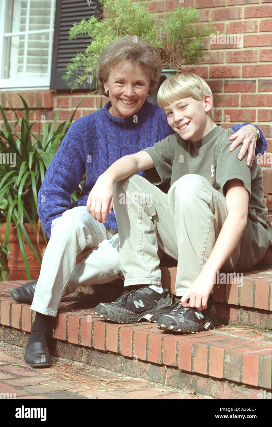 A grandmother sits on the steps of her house talking to her pre ...