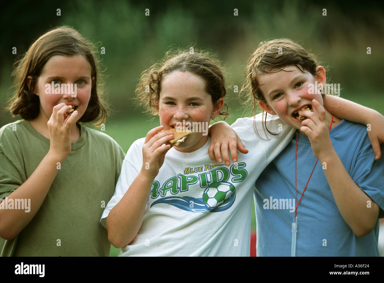 Three girls are standing together with their arms around each other as ...