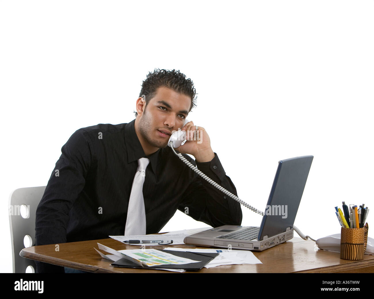 Attractive young business man at his desk with a lap top computer and ...
