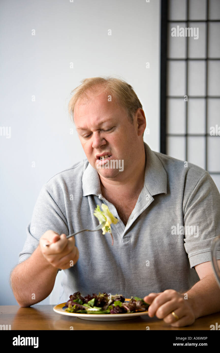 Man looking at his salad with disgust clearly unhappy with the food on ...