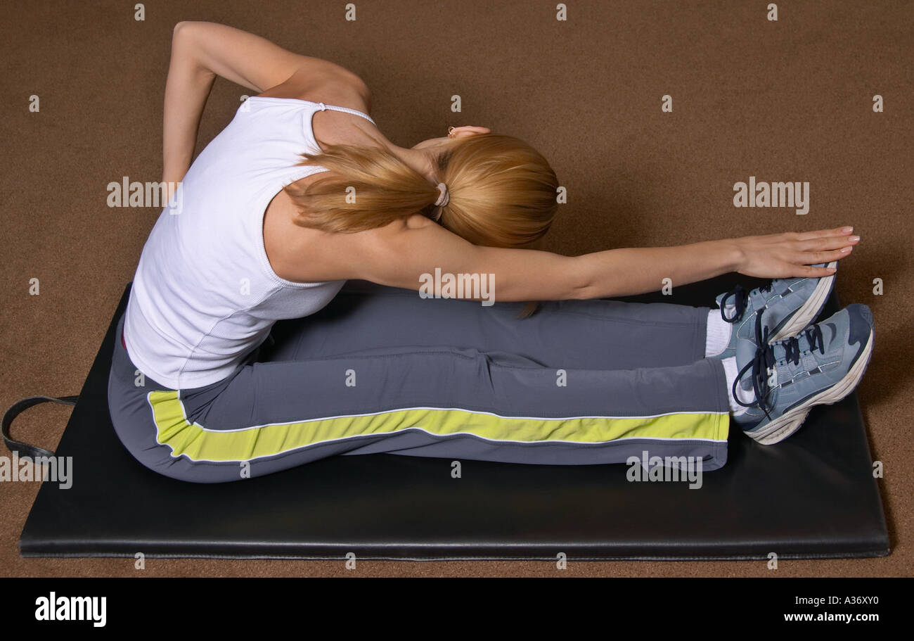 Fit woman completing her workout with a good stretch on a thick mat on ...