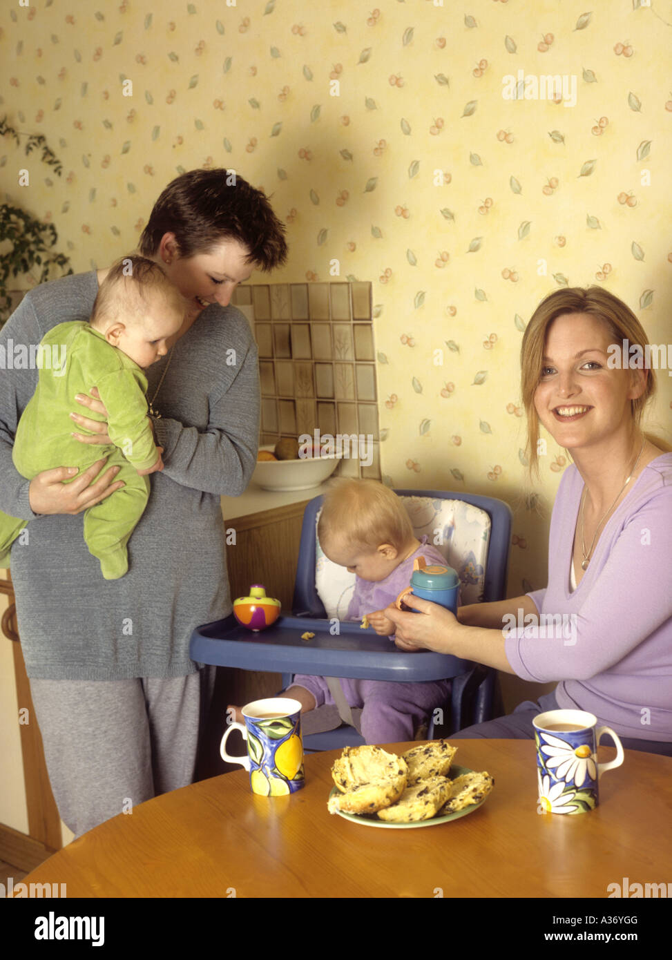 Women with their babies chatting and laughing together in a kitchen ...