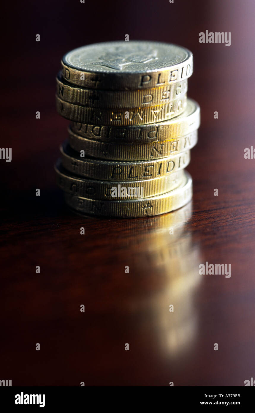 Pound Coins in a pile sitting on top of a highly polished dark coloured ...