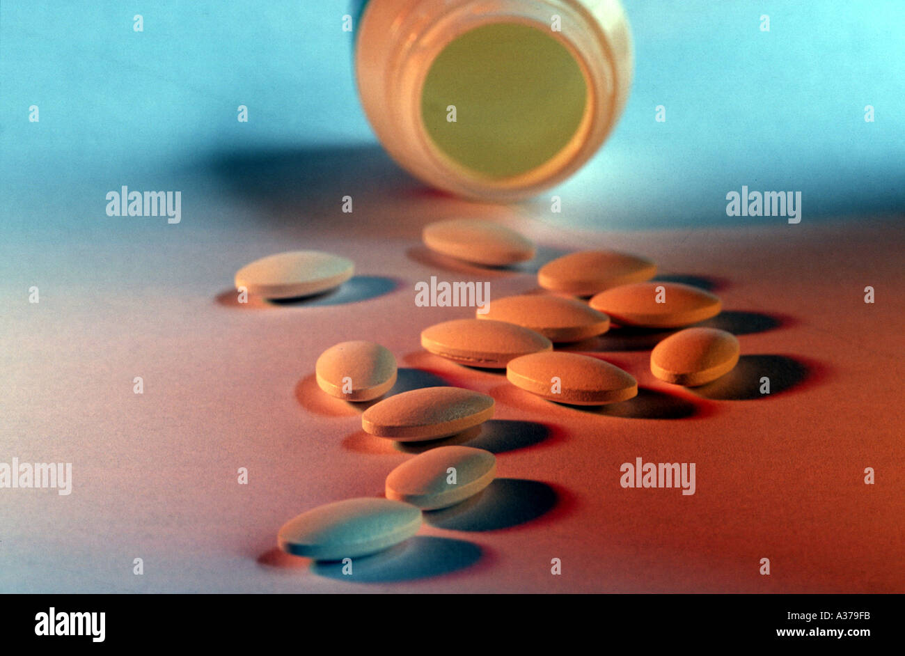 Pills spilling from a tablet bottle on multi coloured background Stock ...
