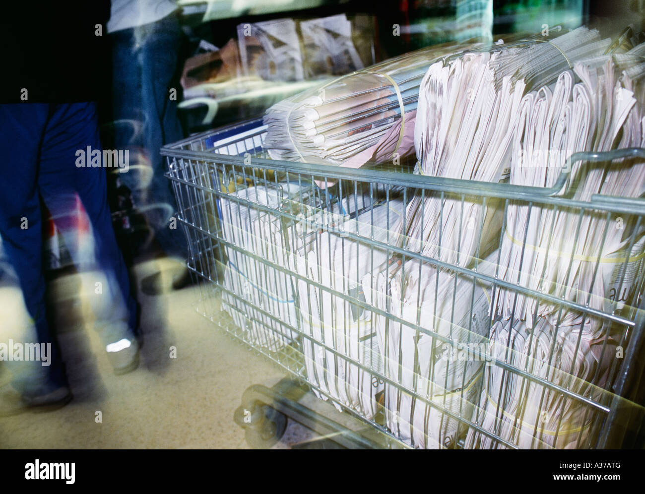 Shopping trolley full of newspapers in supermarket surrounded by ...
