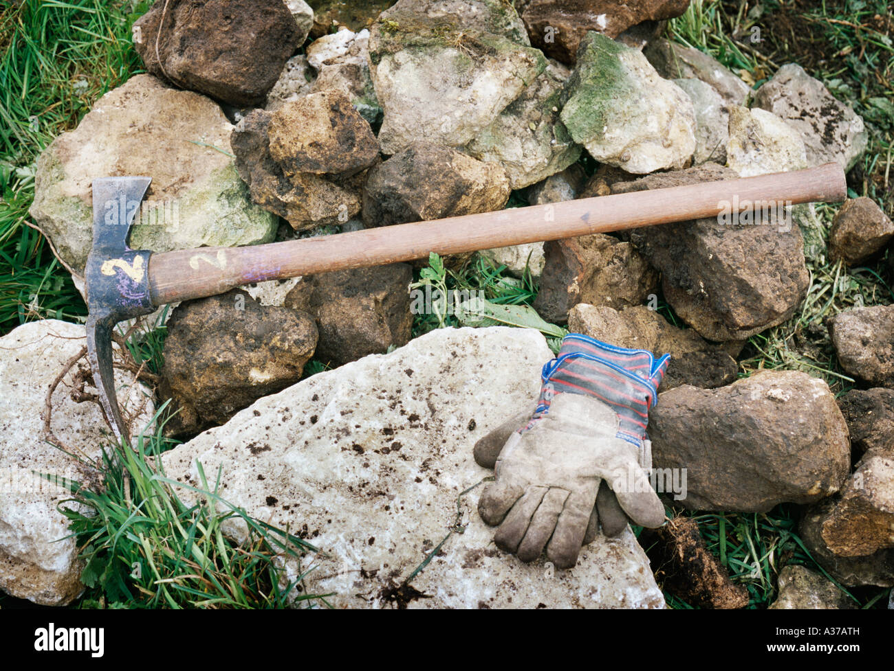 Pick axe and gloves on dry stone wall Stock Photo - Alamy