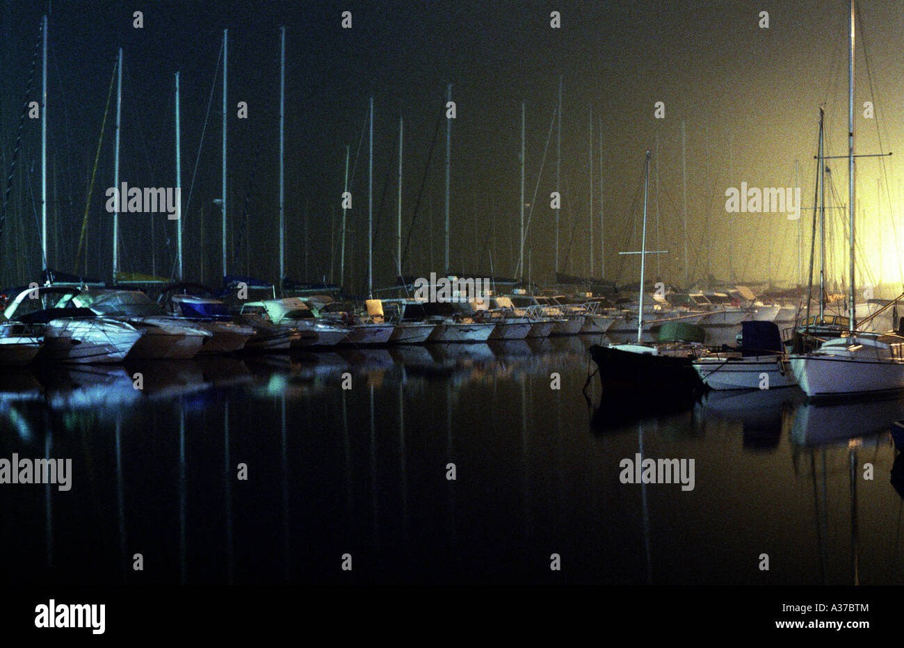Boats lined up in a row at the harbour during night Stock Photo - Alamy