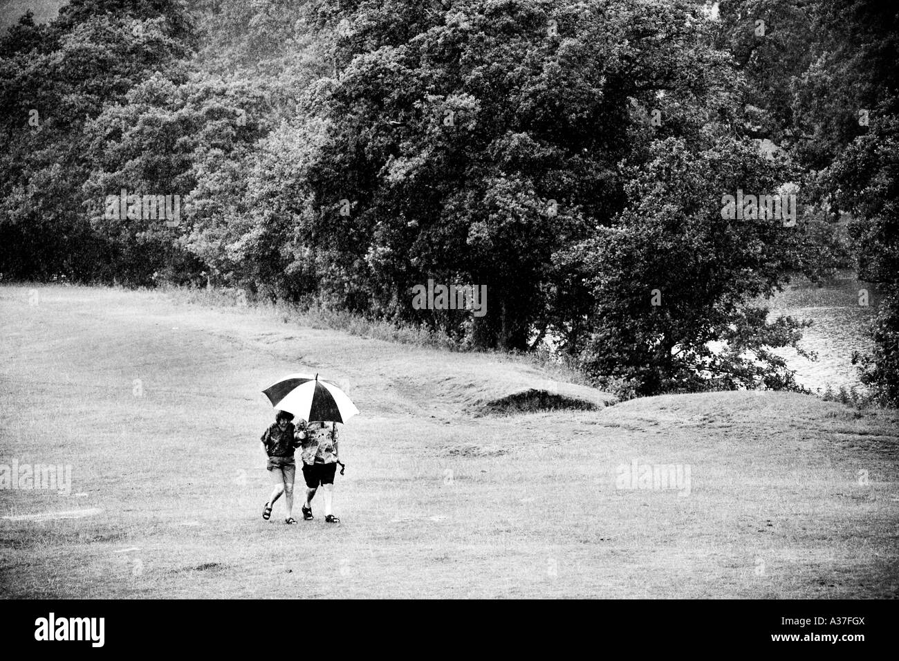 Couple huddle together under umbrella Black and White Stock Photos ...