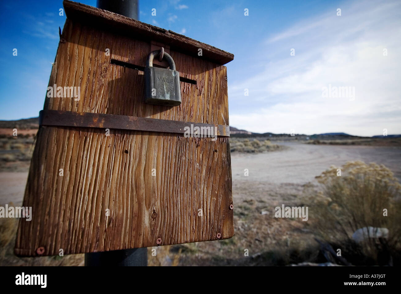 Weathered and beaten wooden box with a Yale lock on it with a dirt road ...